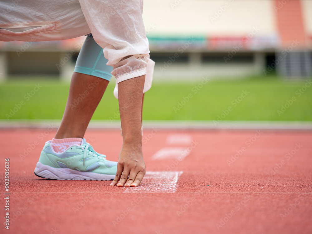 Poster Athlete in starting position on a track, wearing light blue ...