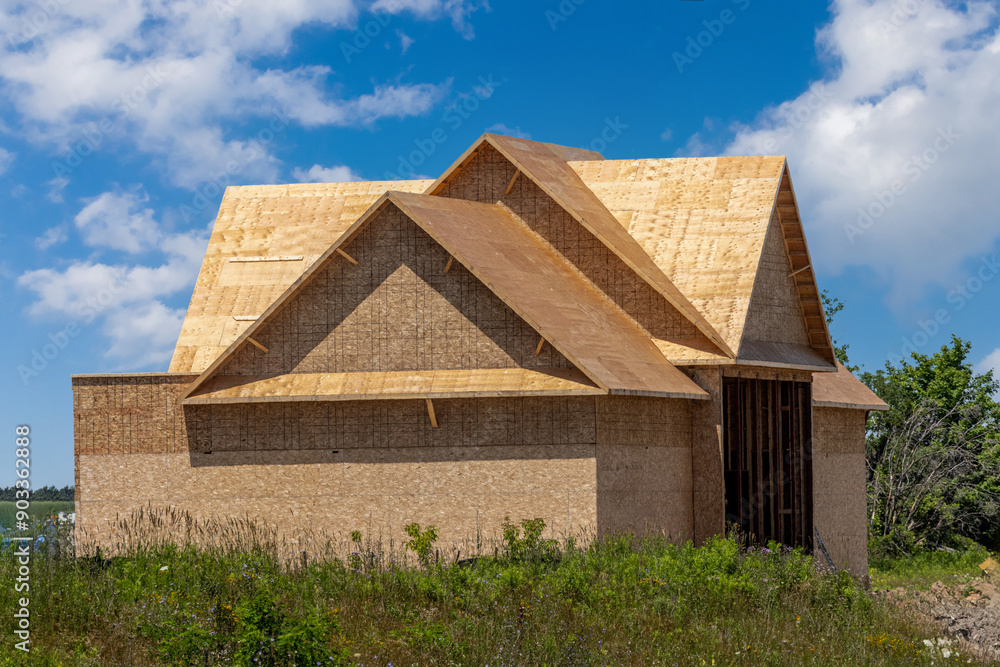 Construction of a small house in a green field showing plywood wall and ...
