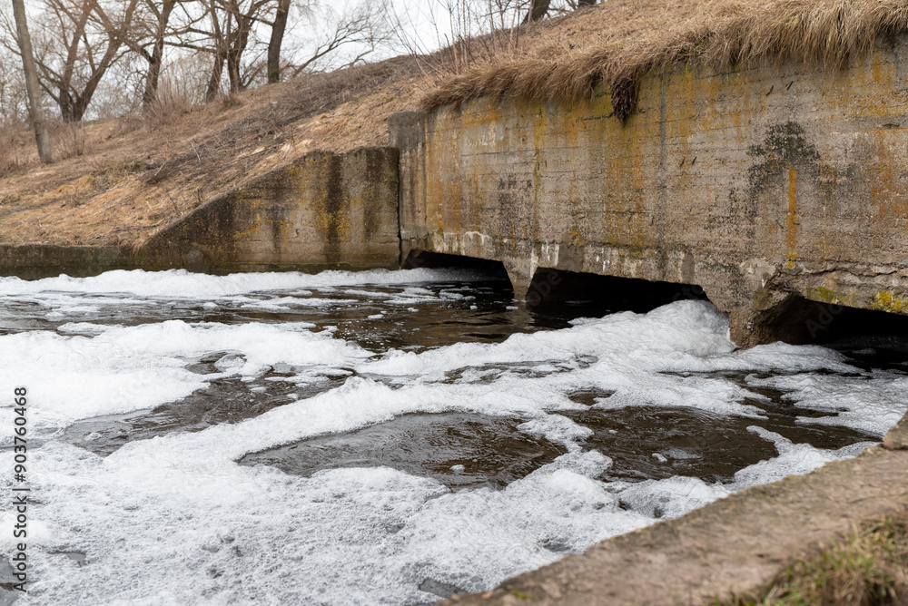 Dam on a small river, a lot of white foam on the water surface. Concept ...