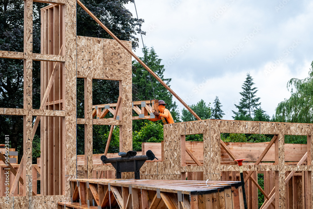 Residential house construction, boom crane lifting lumber delivery ...