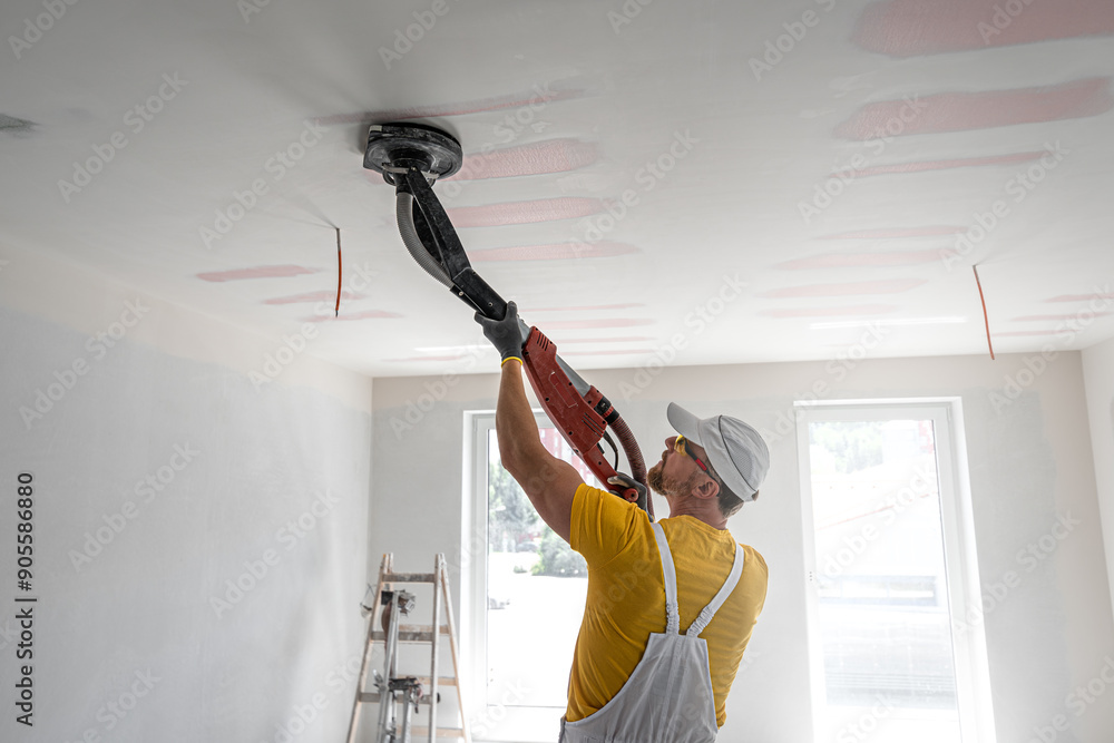 The worker sanding a plasterboard ceiling. He is using special drywall ...