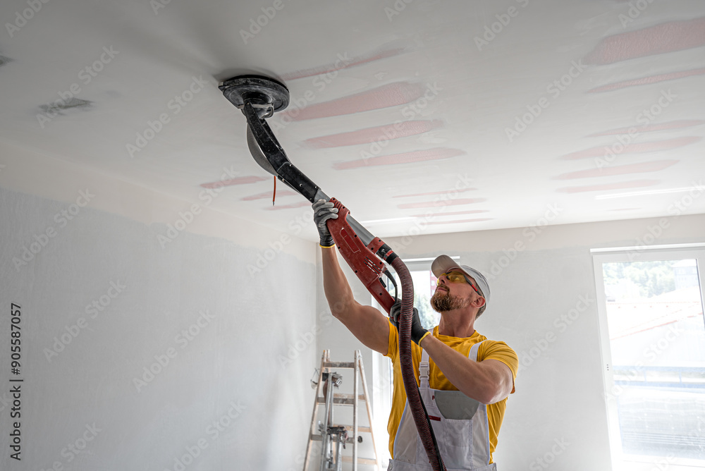The worker sanding a plasterboard ceiling. He is using special drywall ...