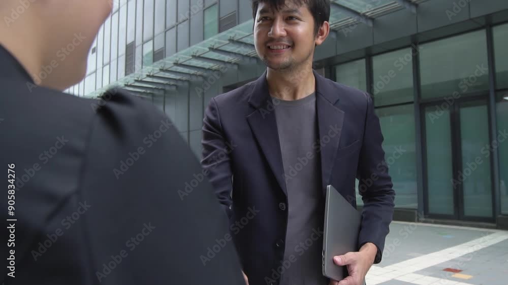 Asian male businessmen holding hands behind an office building business ...
