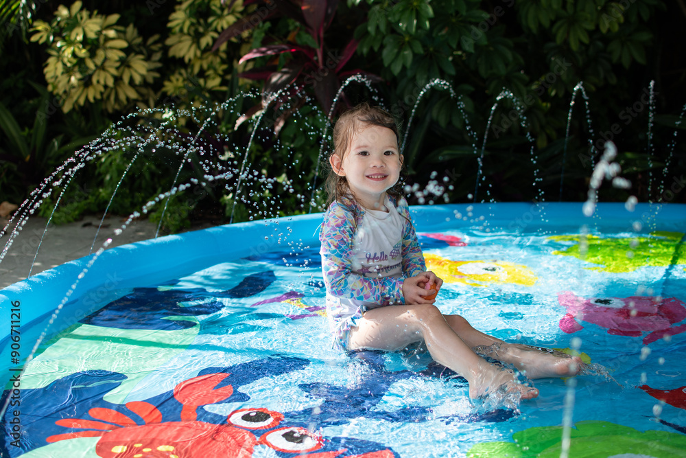 Cute Caucasian little girl playing in a kiddie pool. Summer fun concept ...