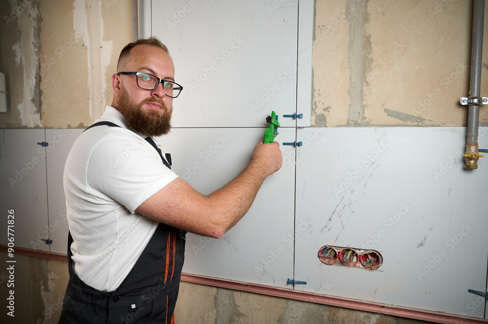 Laying Ceramic Tiles. Tiler placing ceramic wall tile in position over ...
