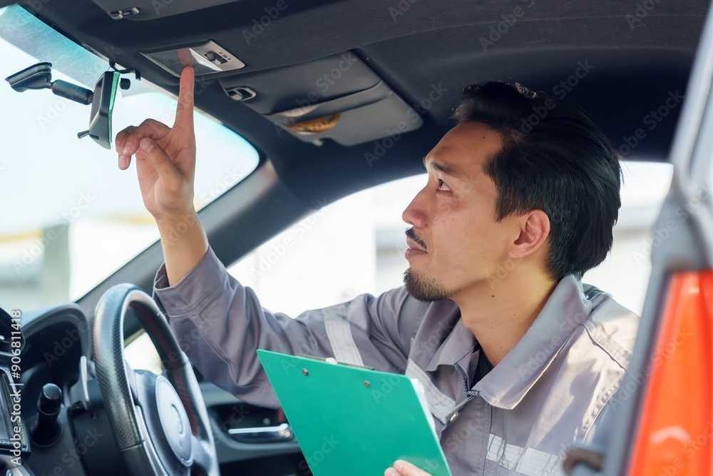 Asian male insurance officer in uniform using clipboard to inspect car ...