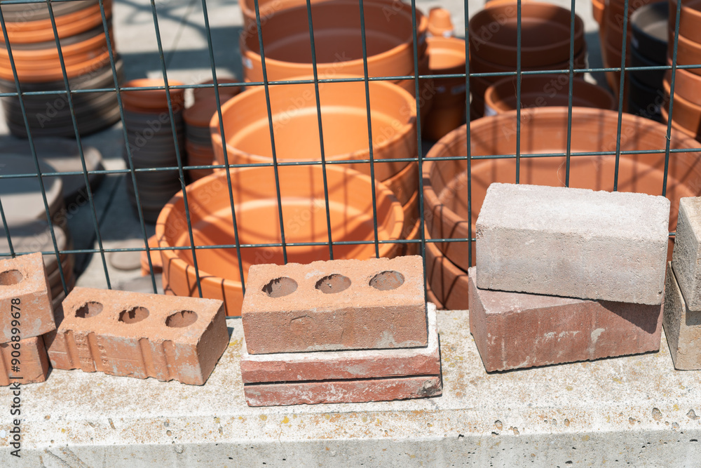 bricks on a short parapet wall, barrier wire mesh fence, and empty clay ...