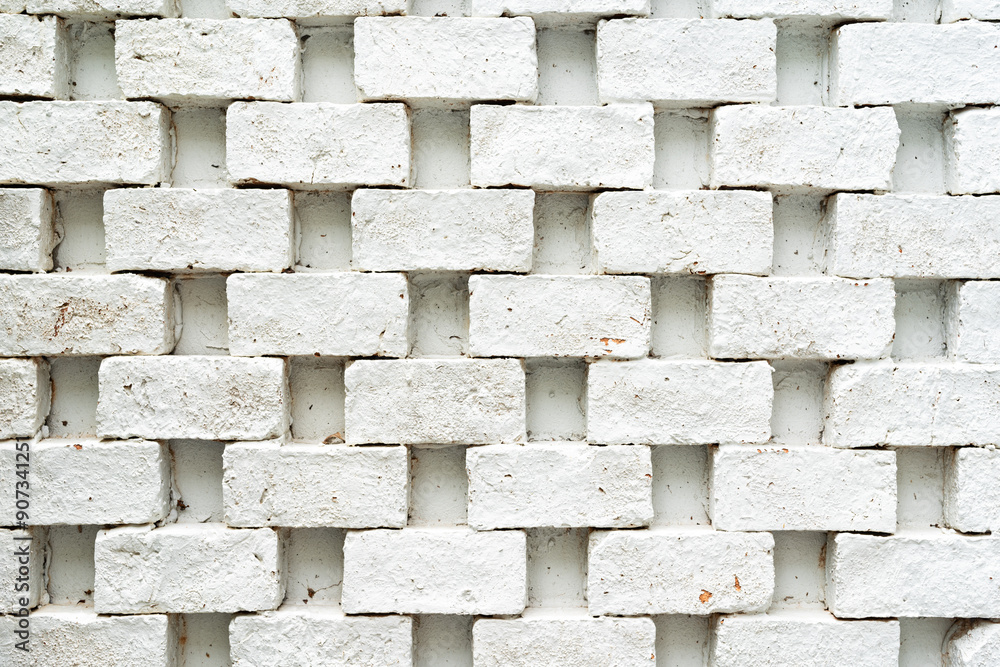 A white brick wall. The bricks are arranged in a regular pattern, with ...