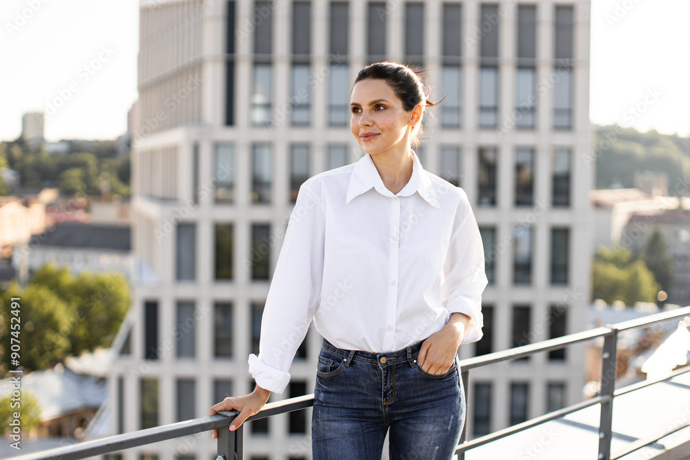 Confident woman standing on rooftop in urban setting looking away ...