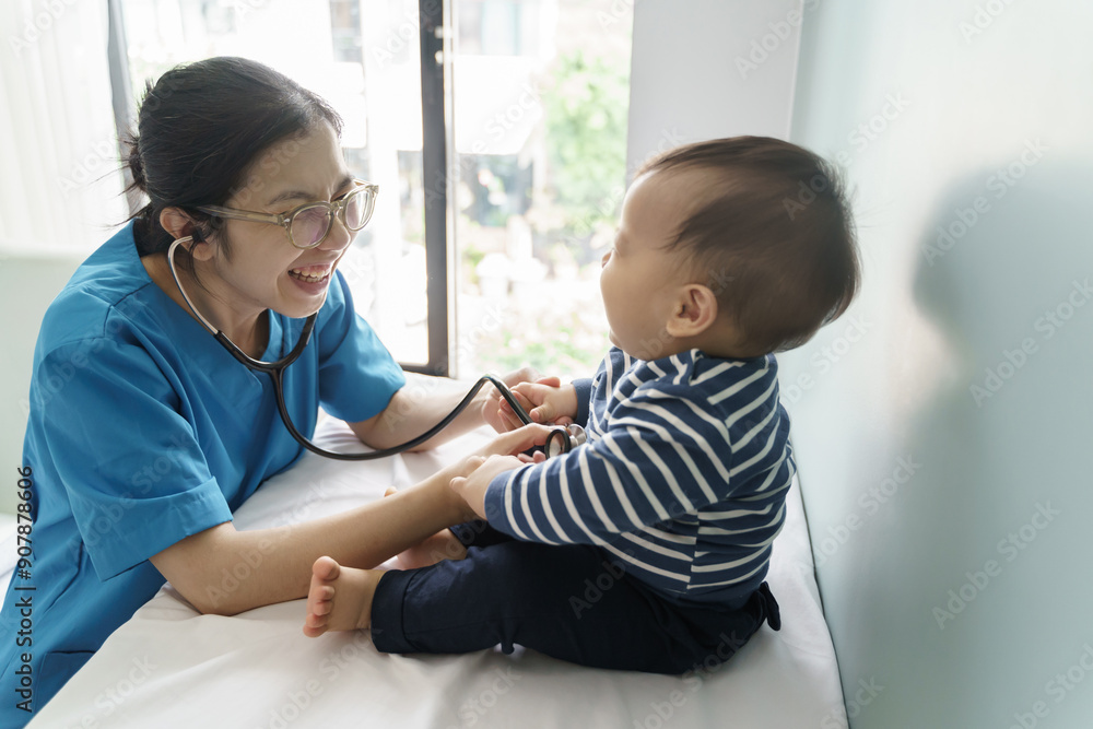 Asian Smiling pediatrician interacting with baby during checkup in ...