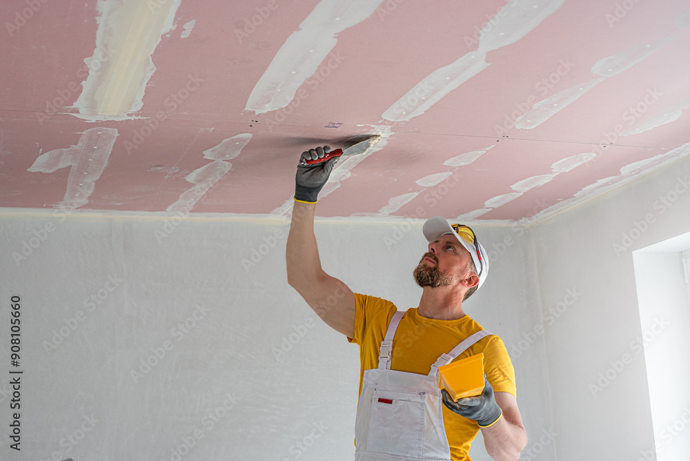 The worker make a plasterboard ceiling. He does taping plaster drywall ...