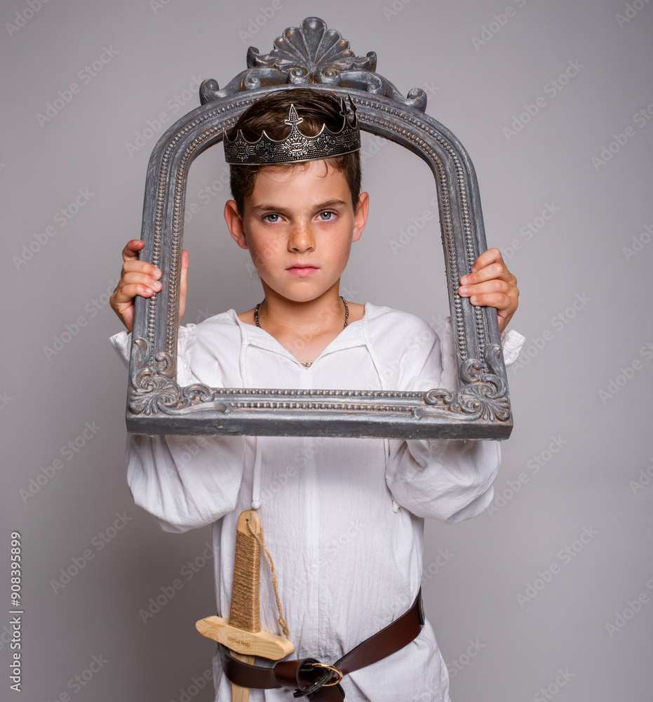 Cute young boy dressed as a prince posing for a royal portrait, holding ...