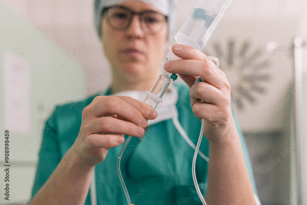 Medical professional in surgical attire preparing intravenous IV drip ...