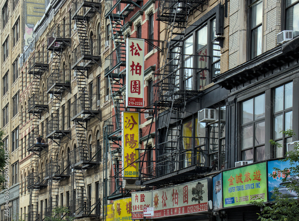 Apartment buildings with fire escapes and store signs written in ...