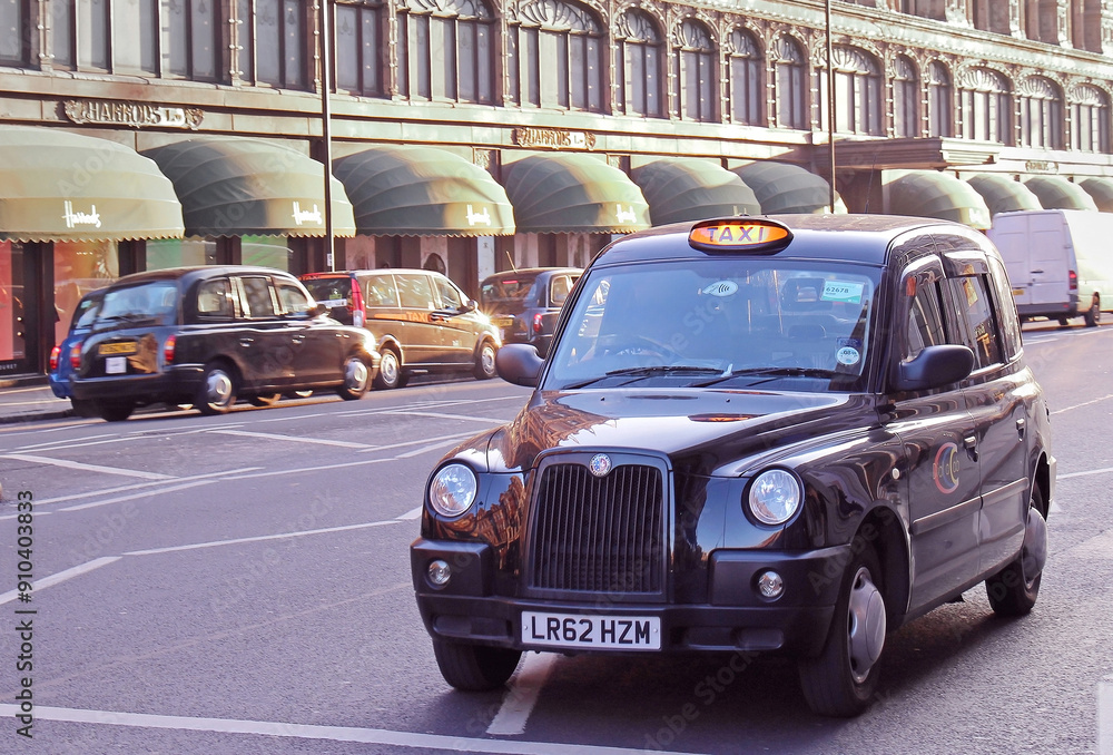 Traditional taxi service black cab car on street with other cars in ...