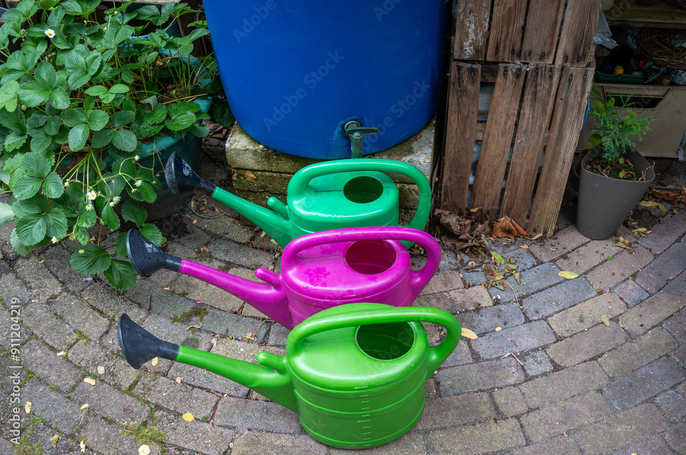 Watering cans in front of a rain barrel, saving rainwater to reuse it ...