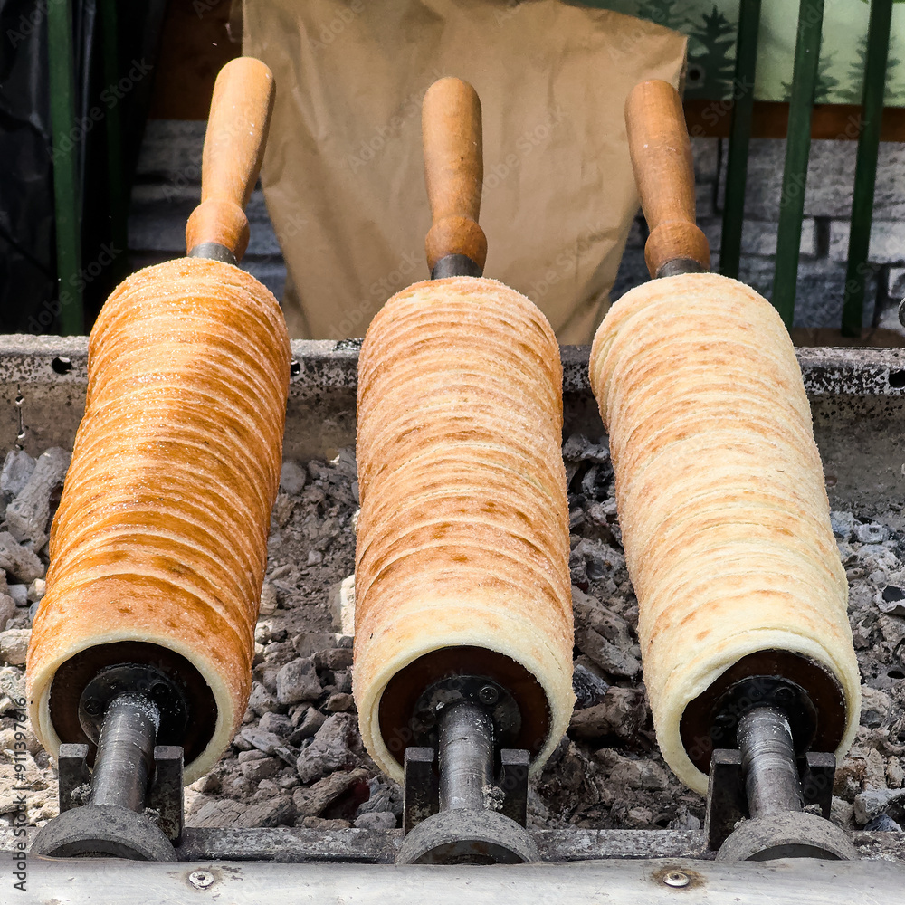 Hungarian chimney cakes (Kürtőskalács) baking on a traditional outdoor ...