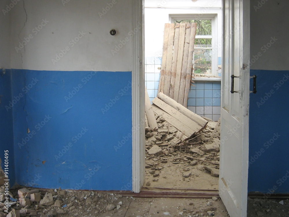 Garbage behind an open door in an empty room in an abandoned house ...