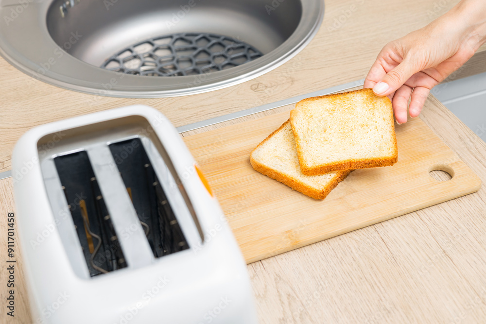 housewife frying bread in a toaster, in the kitchen. woman making toast ...