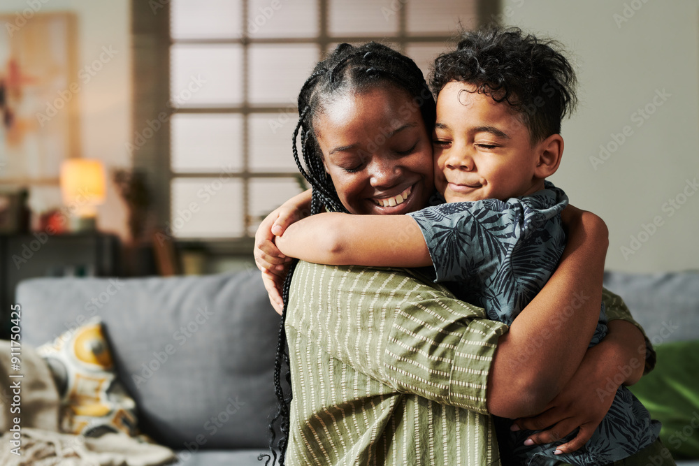 Happy cute little boy in casualwear giving his smiling mother tight hug ...