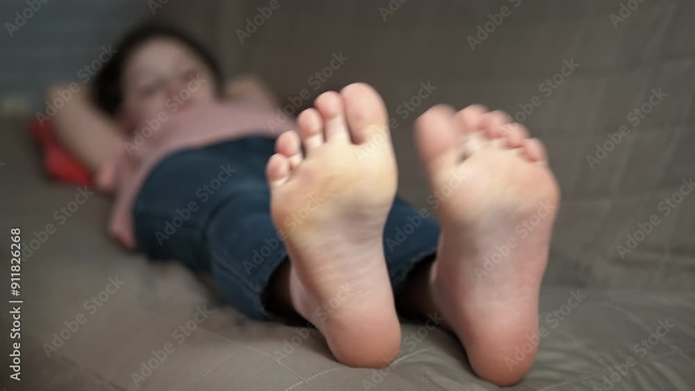 Child feet touch each other. A view of young girl massaging her bare ...