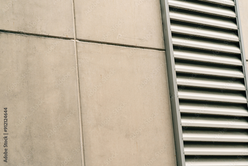 a concrete wall with a vertical metal louver panel running along its ...