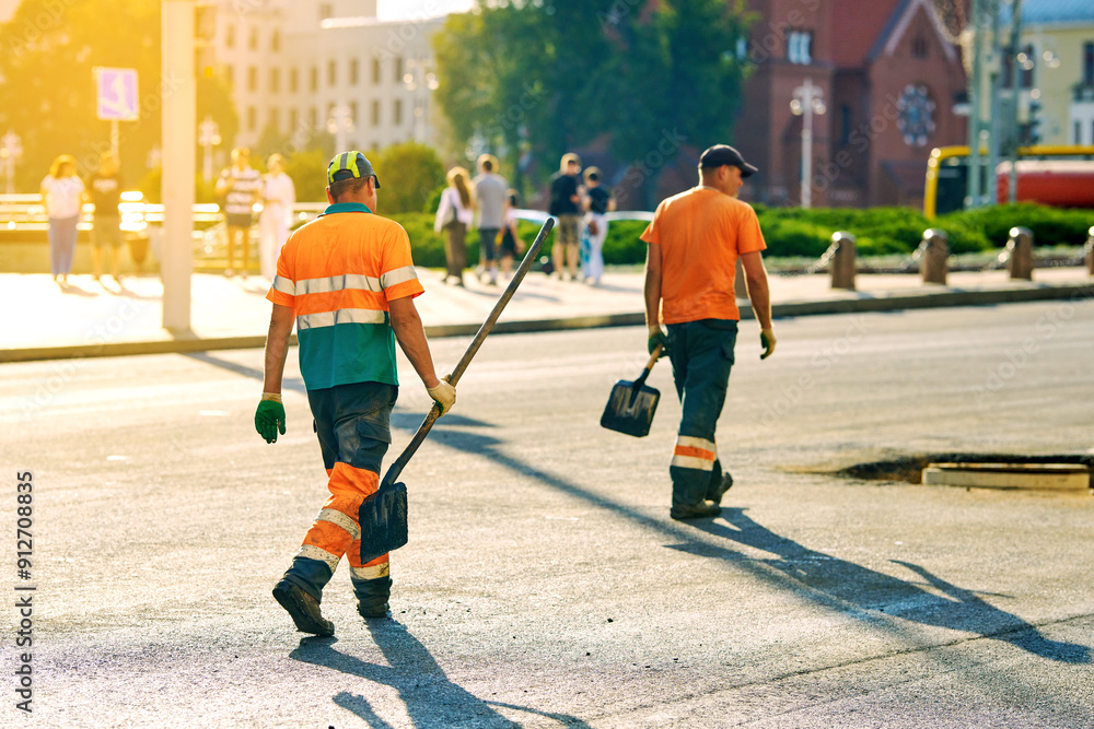 Men with shovels ready to patch asphalt around road hatch, asphalting ...
