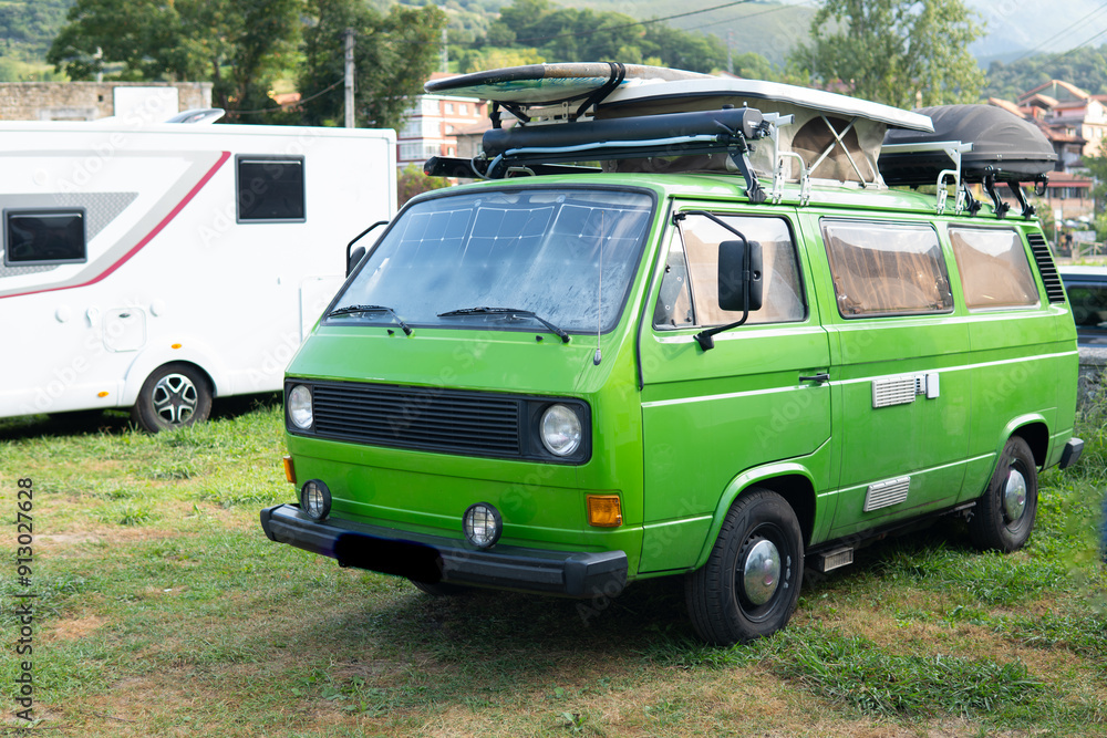 Lime green vintage camper van with surfboards and raised roof next to ...