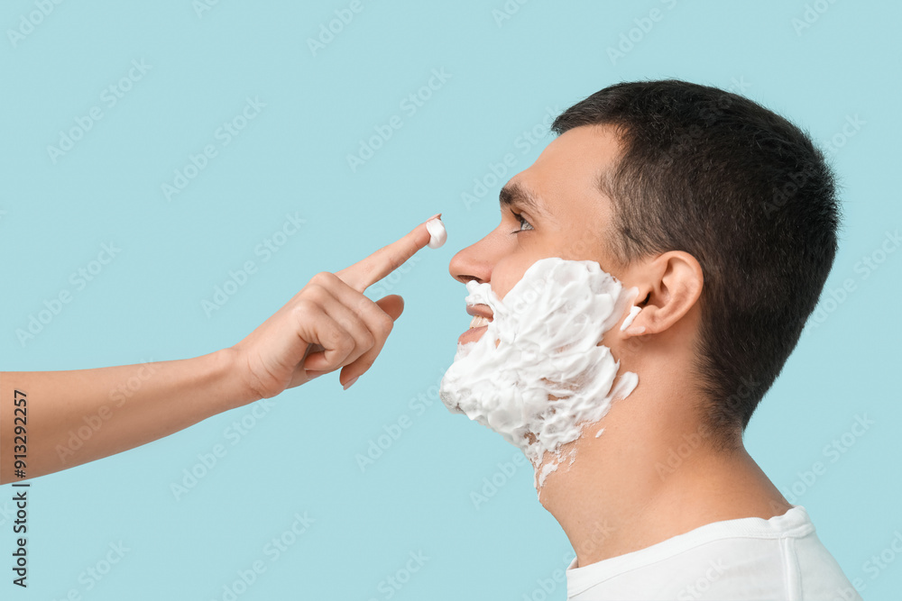 Handsome young man with shaving foam on his face and female hand ...