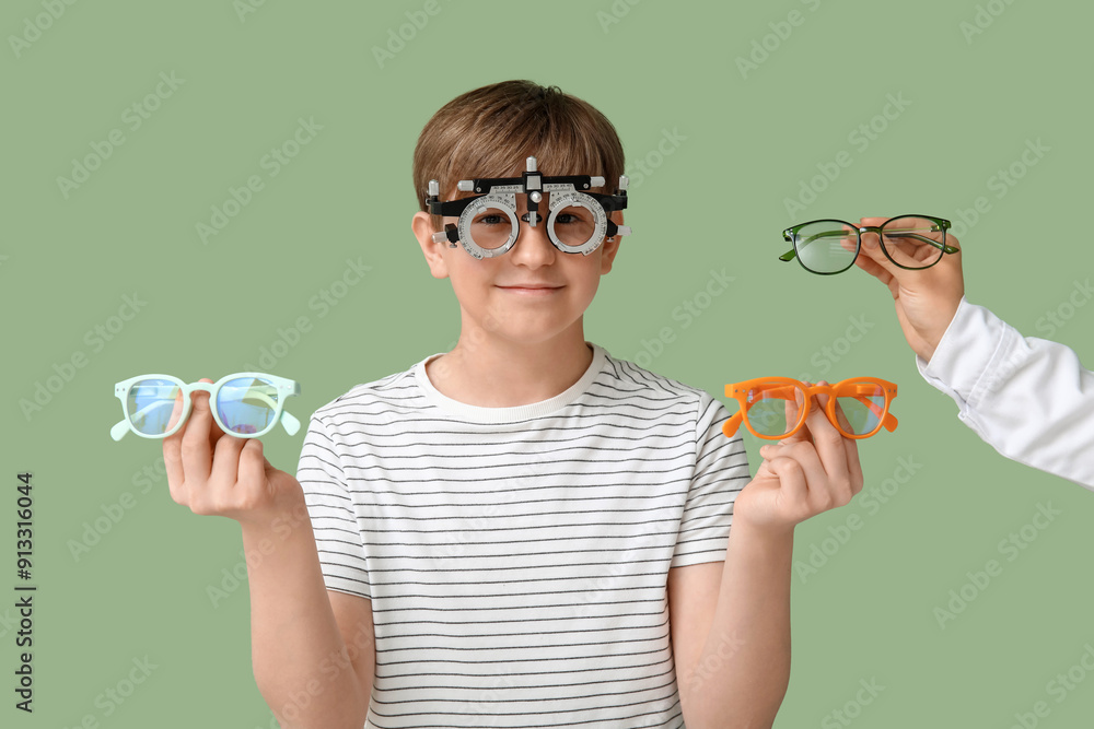 Little boy in optical trial frame choosing between different eyeglasses ...