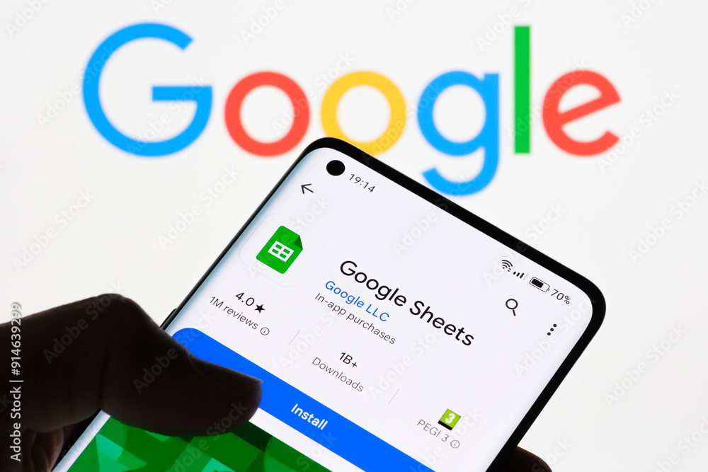 Cellphone screen displaying Google Sheets app with Google logo in the background, illustrating ...