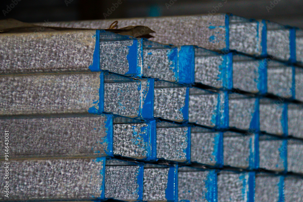 Closeup image of neatly stacked galvanized steel profiles with blue ...