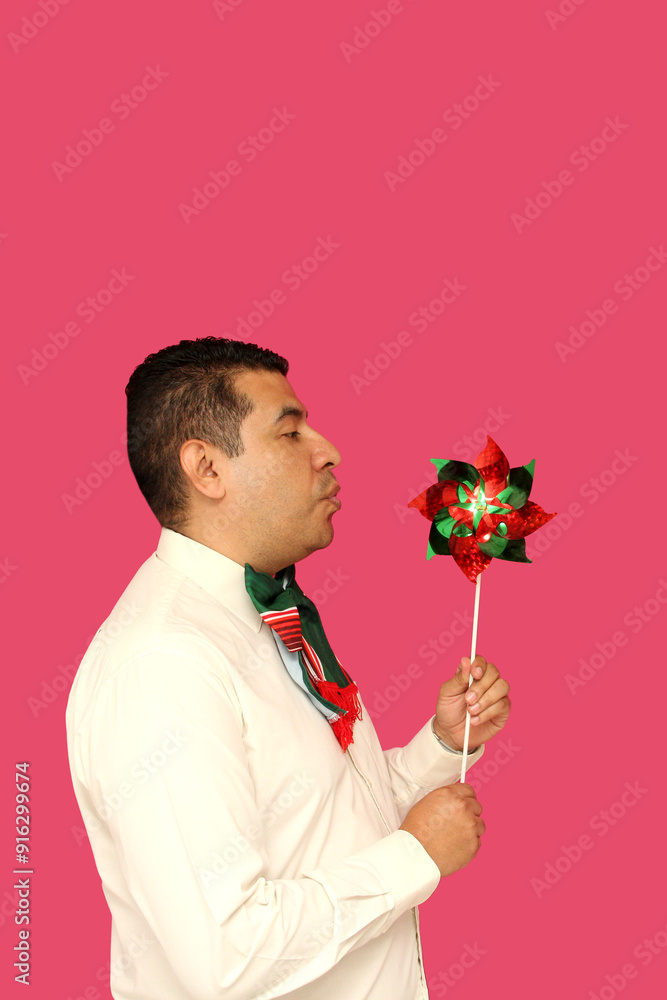 40-year-old dark-skinned Mexican man blows to spin a tricolor pinwheel ...