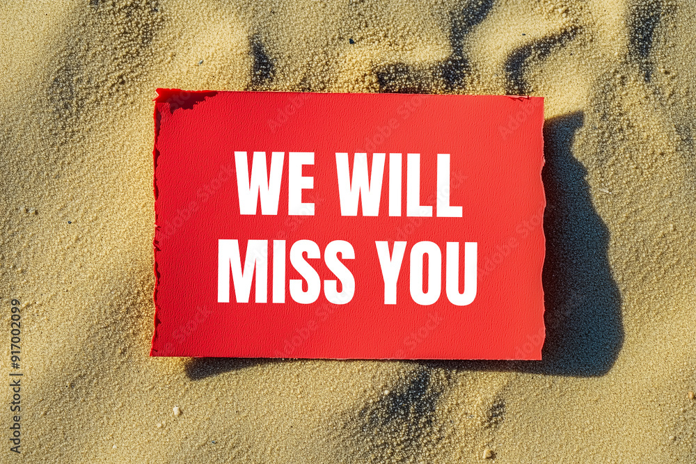 We will miss you message written on red paper on beach sands ...