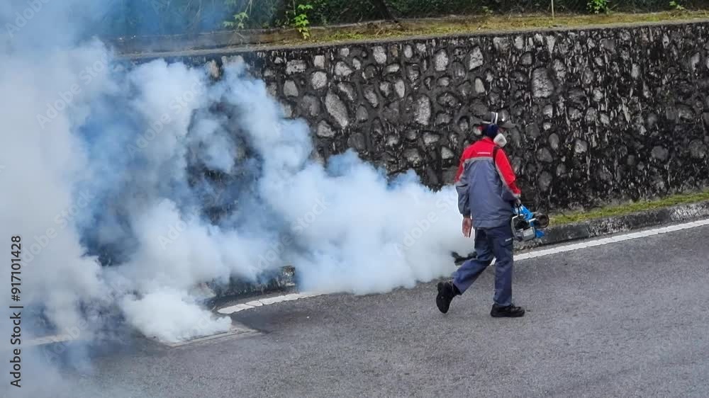 Person fogging insecticides around bushes and drain to kill mosquito ...