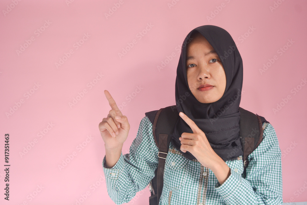Portrait of a muslim schoolgirl carrying books in her hands and wearing ...