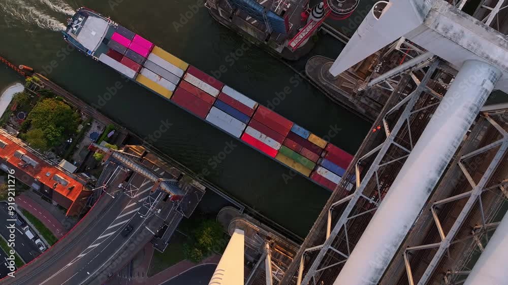 Large container ship passing an open road bridge and lifted rail bridge ...