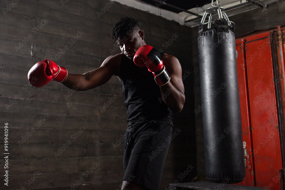 Powerful African American boxer wearing red gloves prepares to hit ...