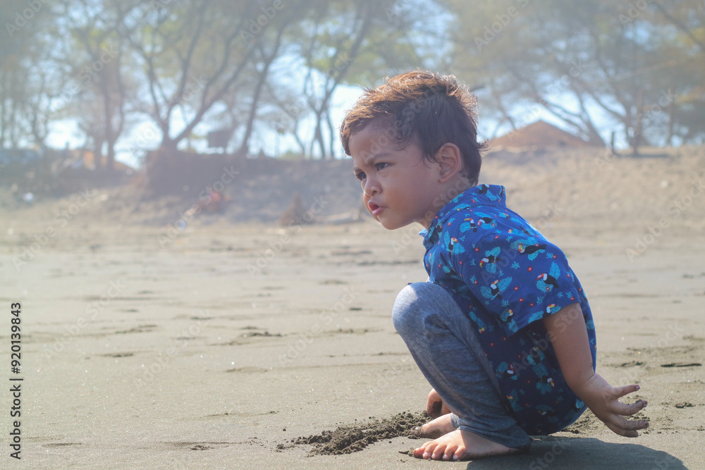 Cute child drawing picture on a sand playing outdoor on summer beach ...