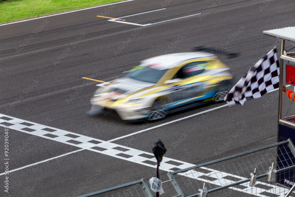 Race car crossing finish line on track and pass checkered race flag ...