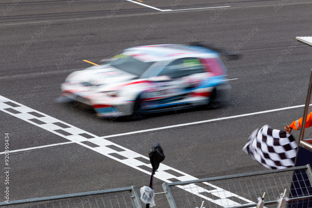 Race car crossing finish line on track and pass checkered race flag, Checkered racing finish ...