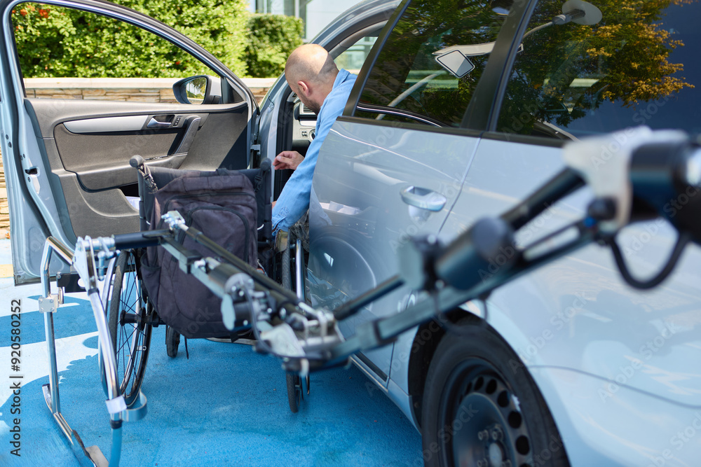 Man using a wheelchair transferring into a car, illustrating accessible ...