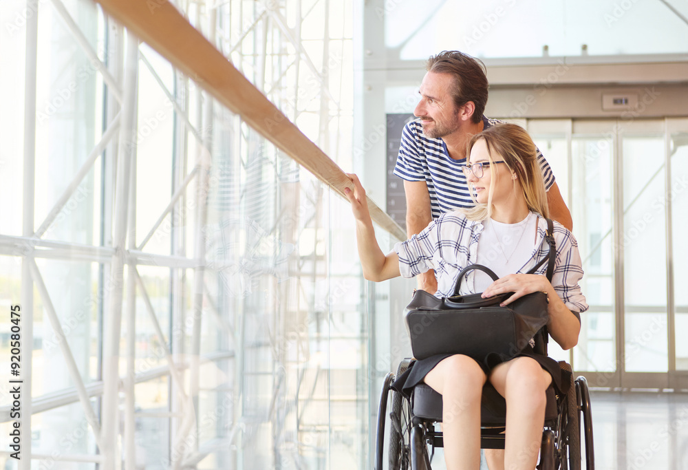 Woman using wheelchair exploring modern building with partner Stock ...
