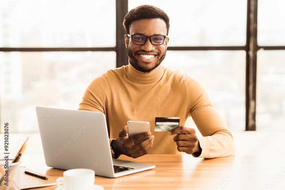 Online Banking. Happy black man holding plastic credit card and mobile ...