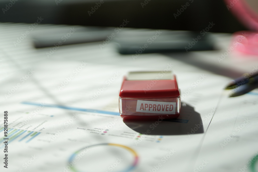 Red approved stamp lying on business documents with charts and graphs ...