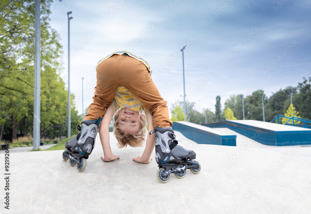 young cute boy stands on roller skates with his head down. learning to ...