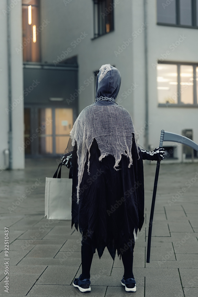 Back view of kid in grim reaper Halloween costume with scythe and bag ...
