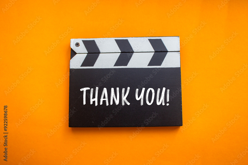 Thank you message written on movie clapper board with orange background ...