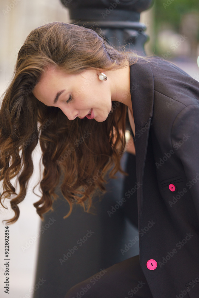 Woman leaning forward with flowing hair, wearing a black blazer, in a ...