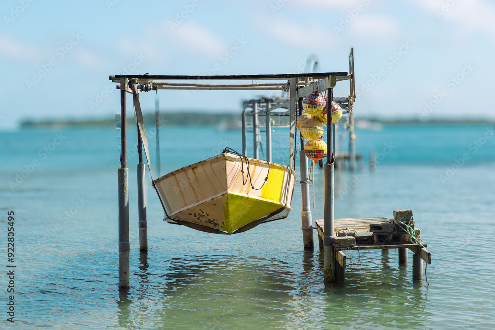 Weather faded boat hangs from a boat lift with colorful buoys hanging ...